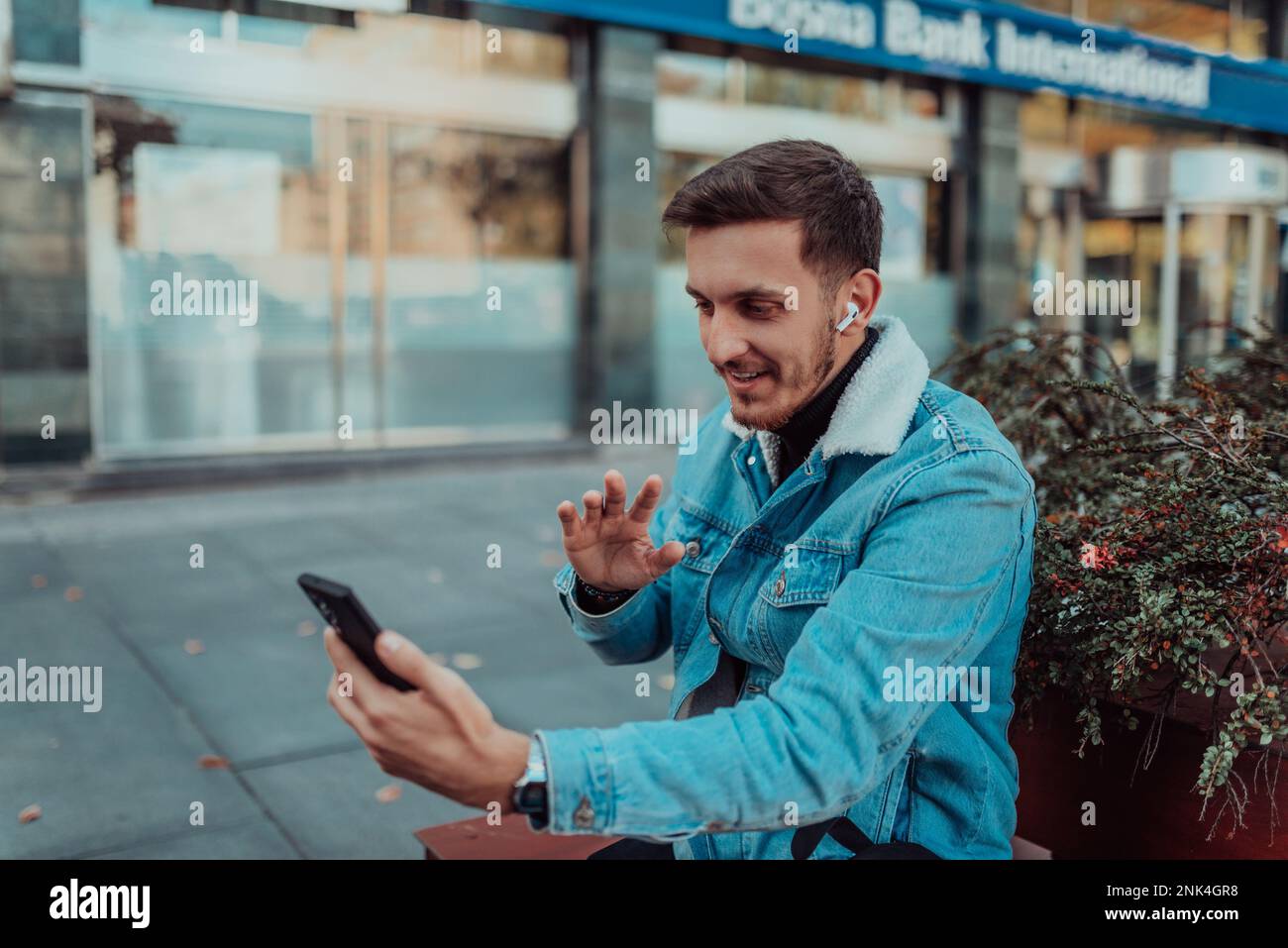A gappy student sitting in a park using a smartphone and wireless ...