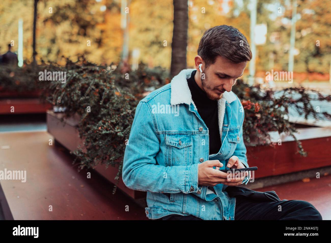 A gappy student sitting in a park using a smartphone and wireless ...
