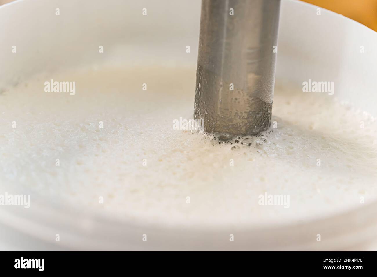 Ice cream preparation. Mixing milk with a blender close view. High ...
