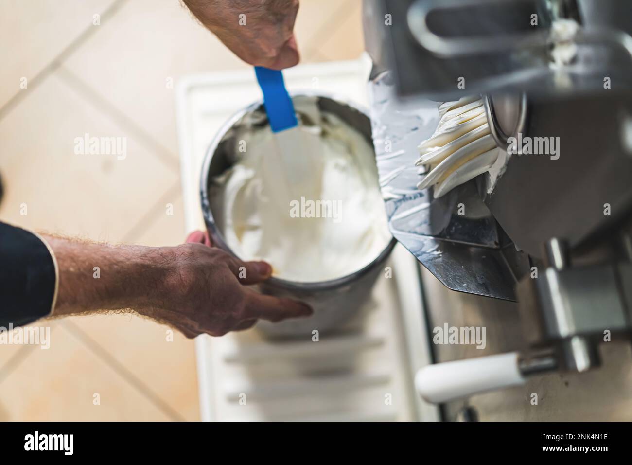 Close shot of man hands with a stirring paddle mixing ice cream from ...