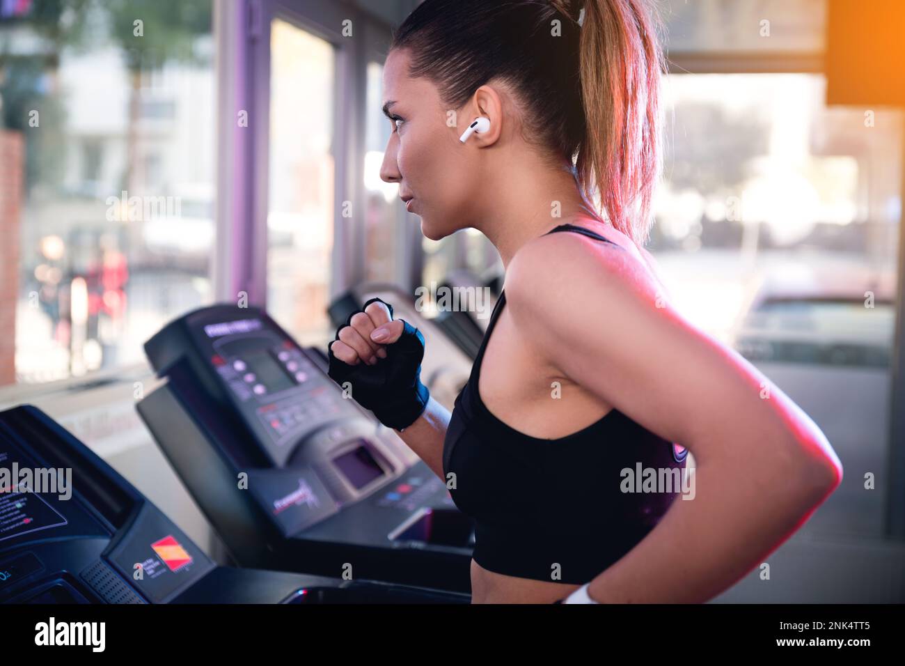 One woman with black tops and bluetooth ear phones running on a tread ...