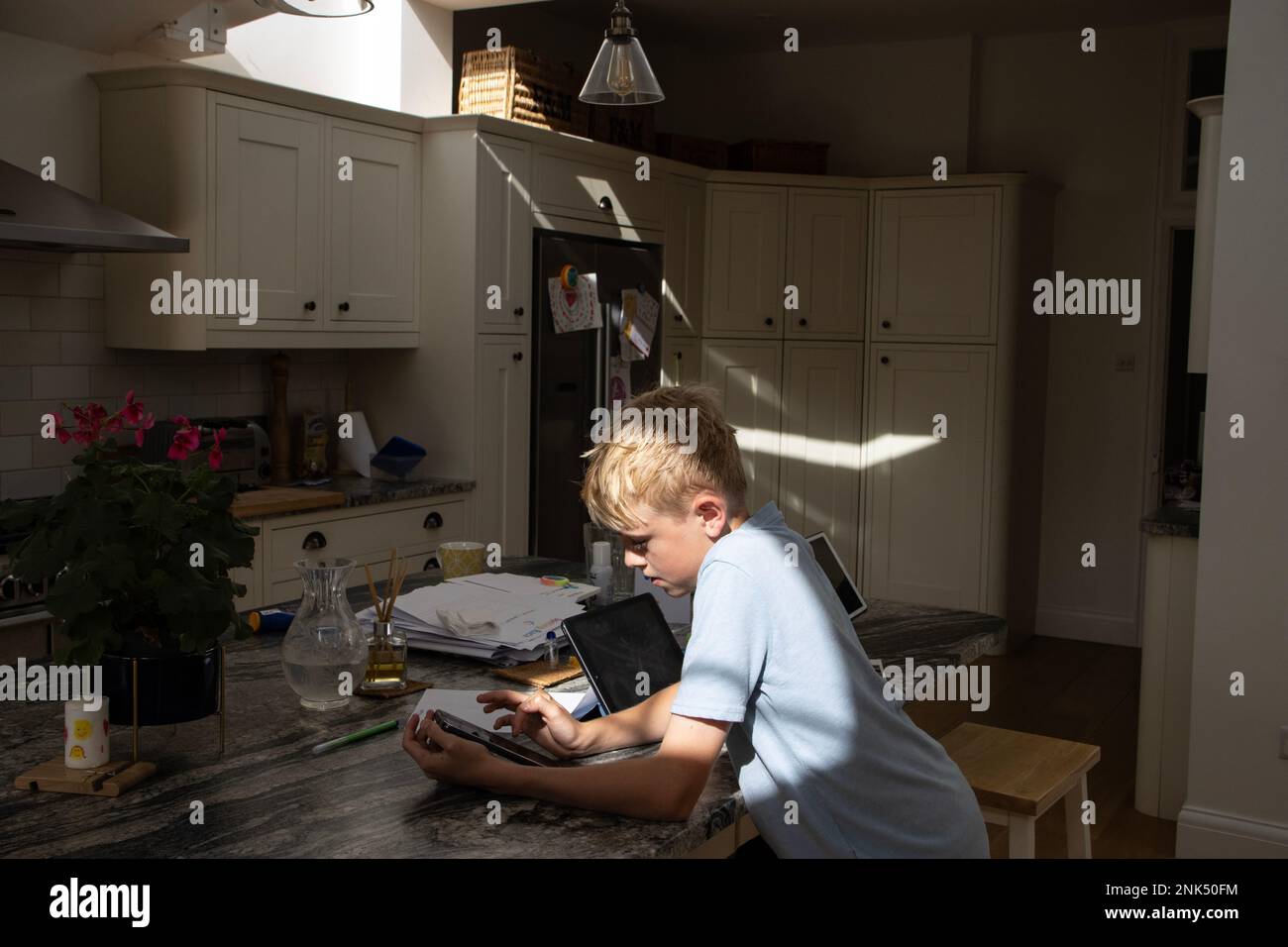 Young boy aged 12, checking his social media on his smartphone, whilst ...