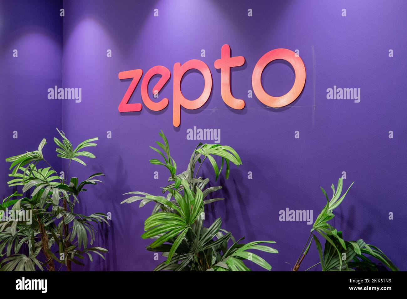 Online startup delivery app Zepto logo on purple wall with plants below ...