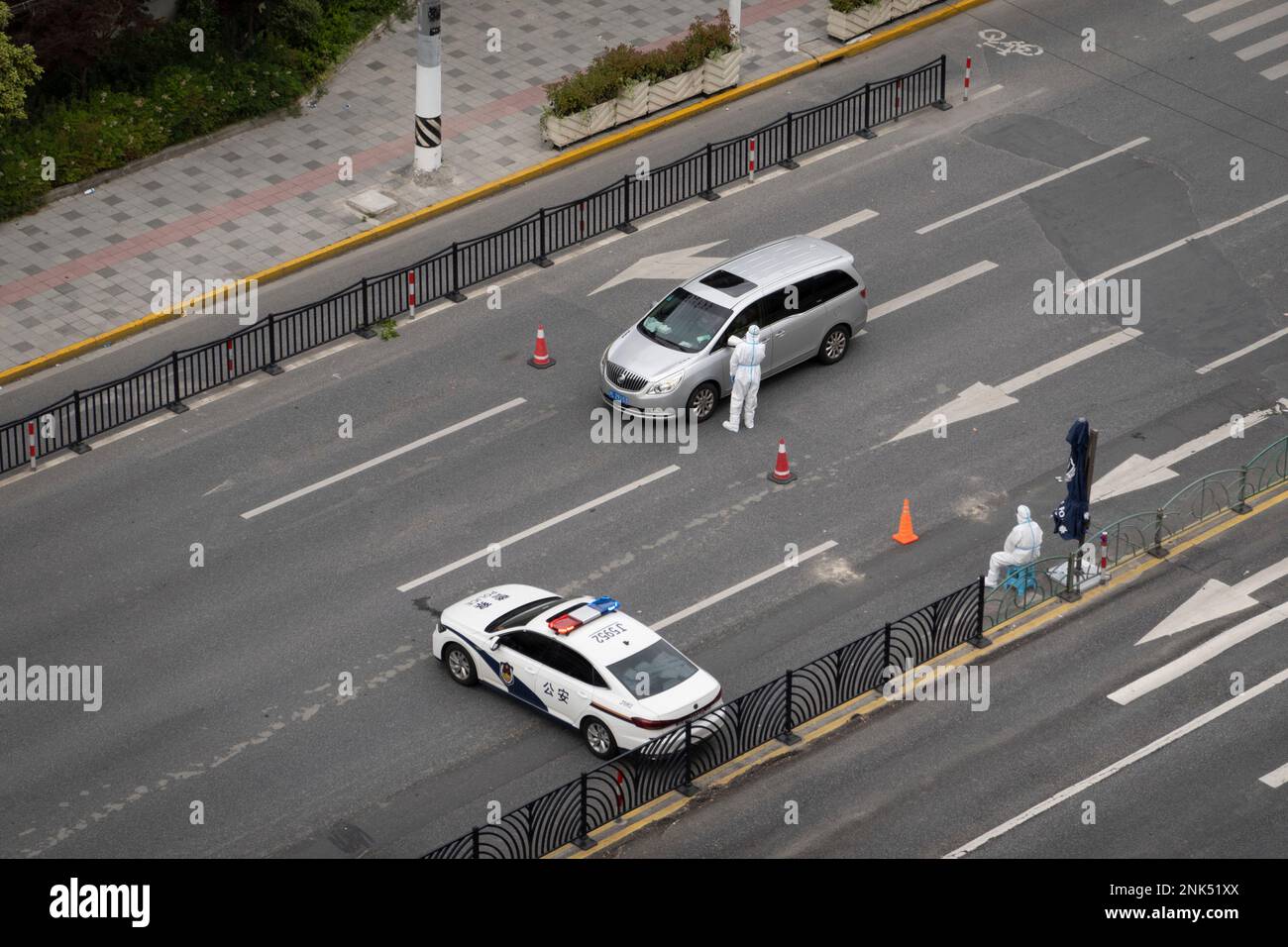 Policemen check passing vehicles for permits at a temporary checkpoint ...