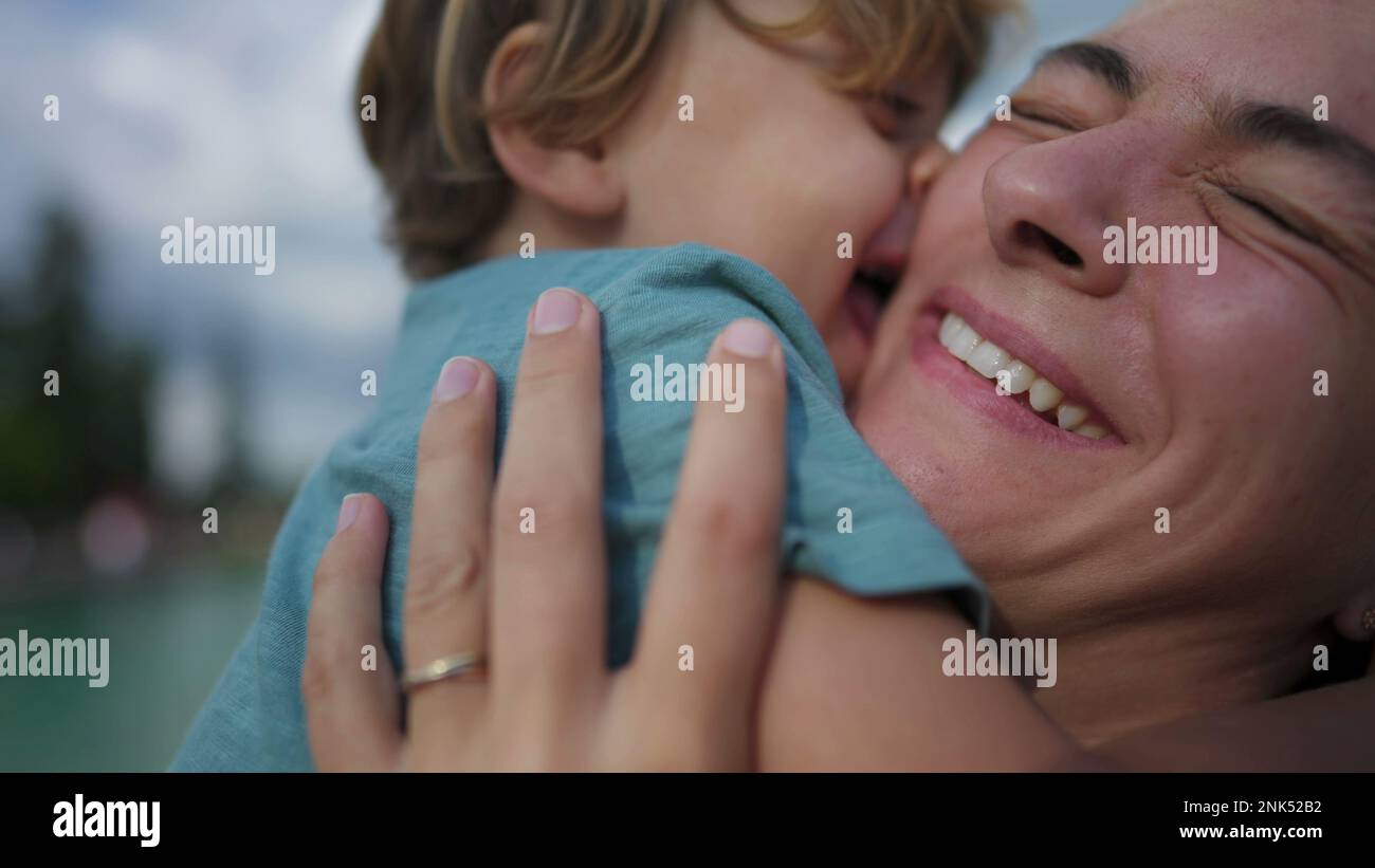 Funny cute moment of child kissing mother in cheek with tongue. Real ...