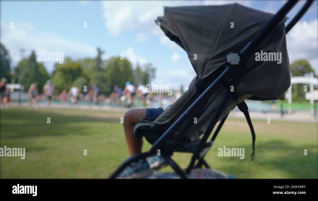 Child napping inside stroller outdoors at park during summer day. Small ...