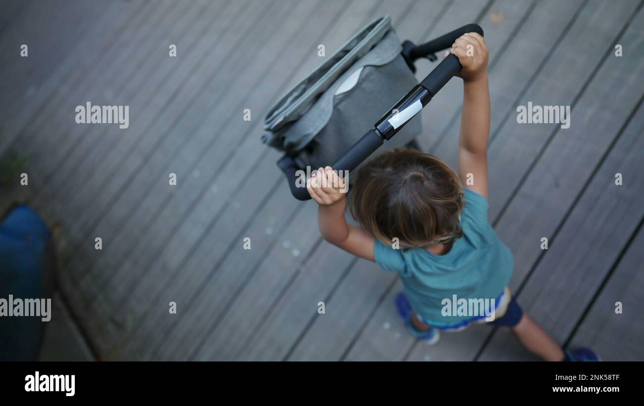 Child pushing stroller. Top view perspective of cute little boy helping ...