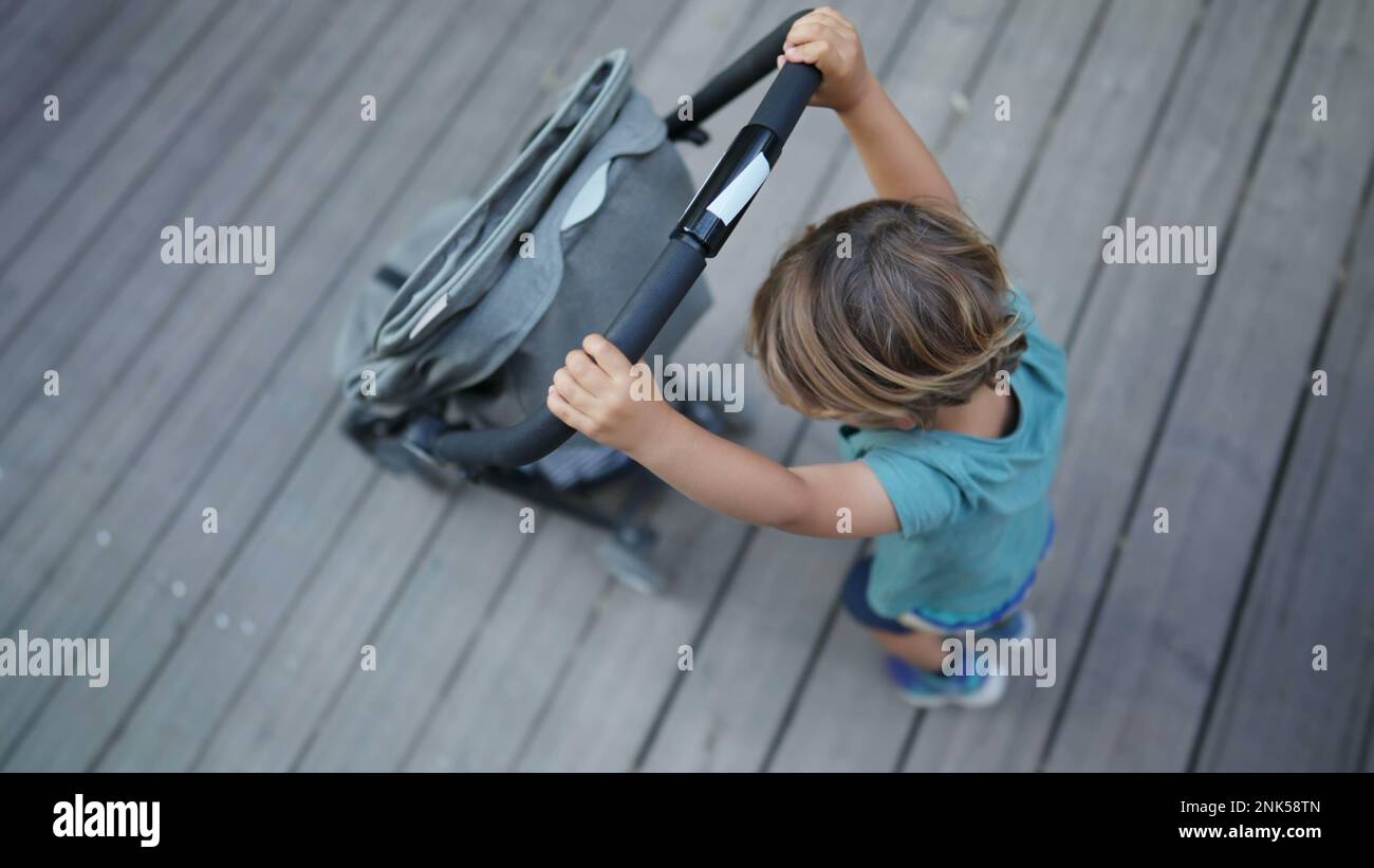 Child pushing stroller. Top view perspective of cute little boy helping ...