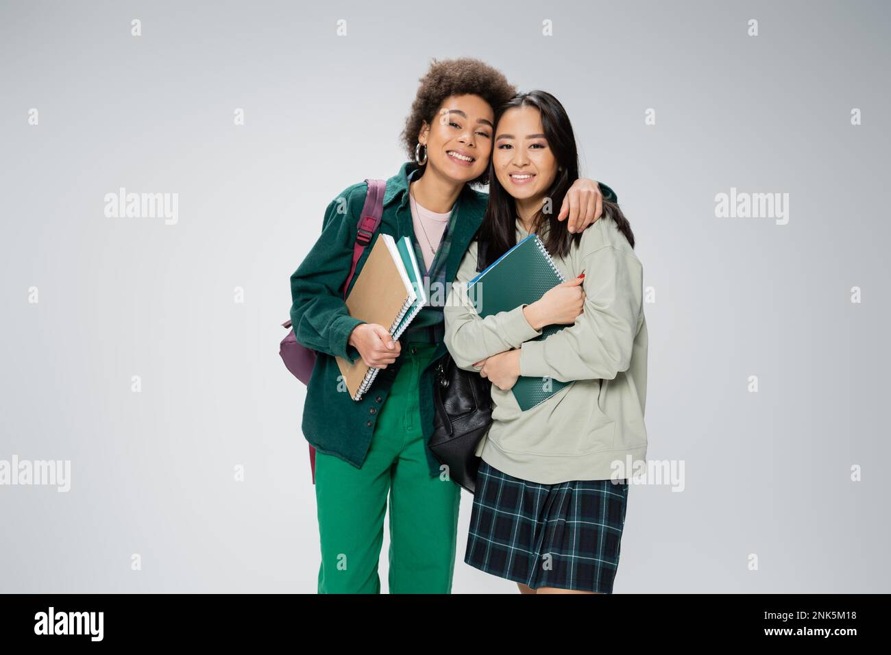 pretty interracial students with copybooks and backpacks smiling at ...