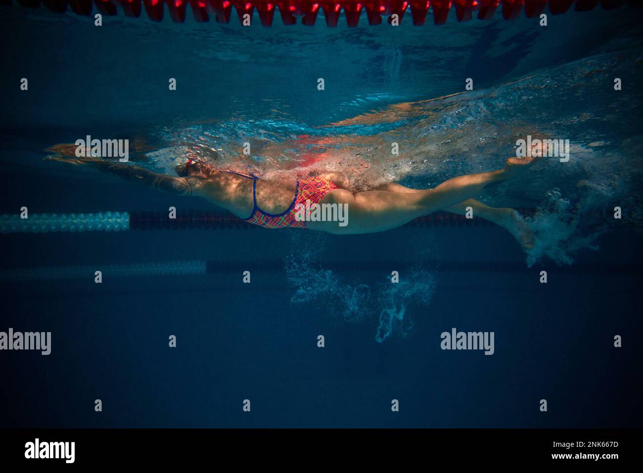 Bubbles. Professional female swimmer in cap and goggles in motion ...