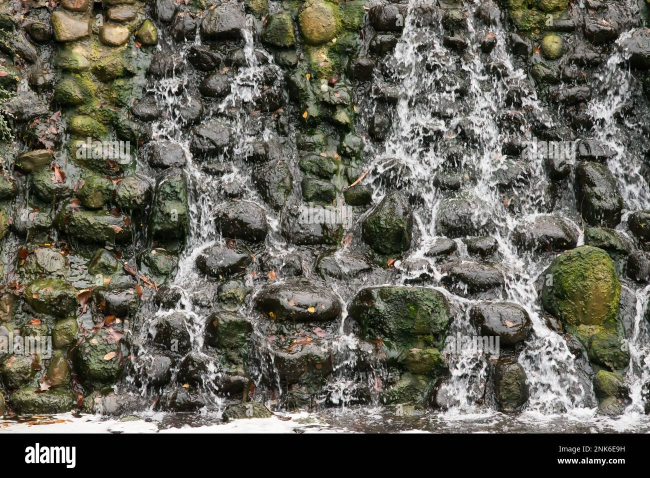 View of a stone wall and water flowing down the wall, a waterfall Stock ...
