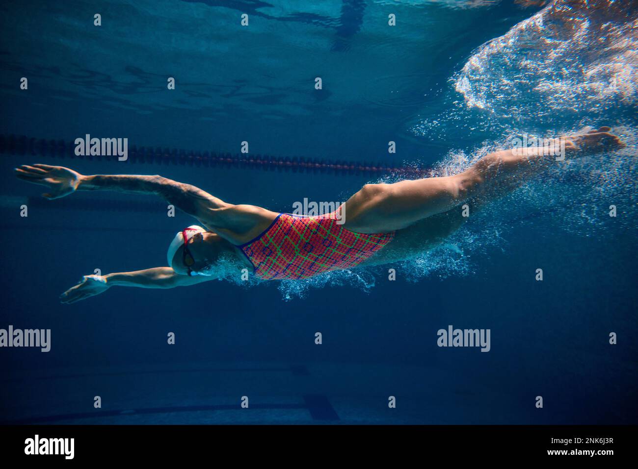 Diving into water. Professional female swimmer in cap and goggles ...