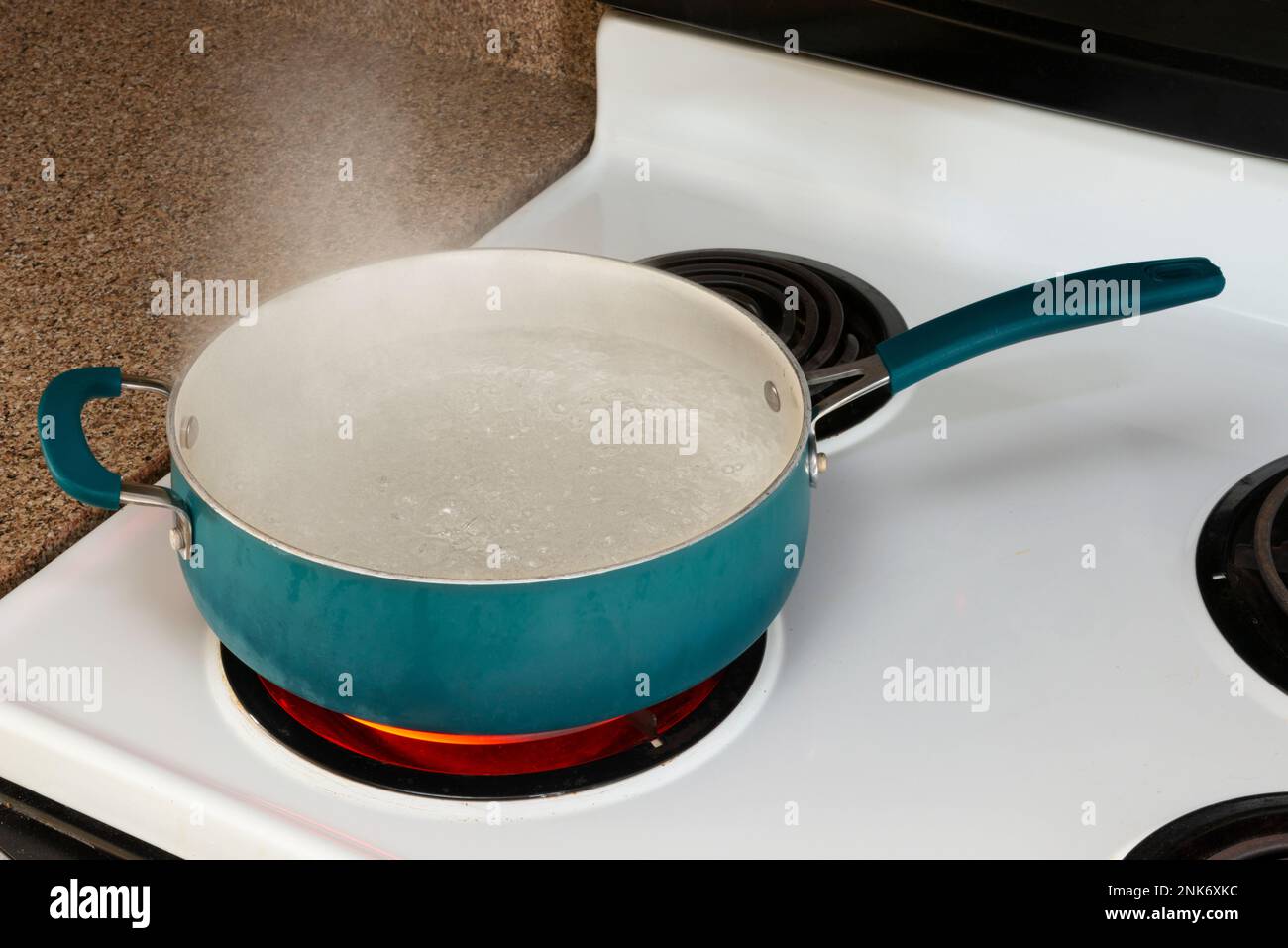 Horizontal shot looking down on a blue pot on a white stove top on a ...