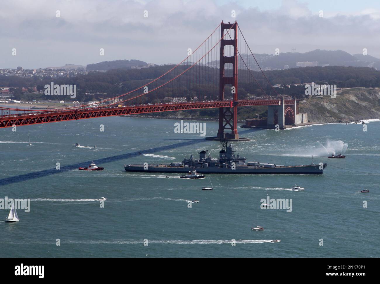 A flotilla of boats escorts the battleship Iowa as it's towed under the ...