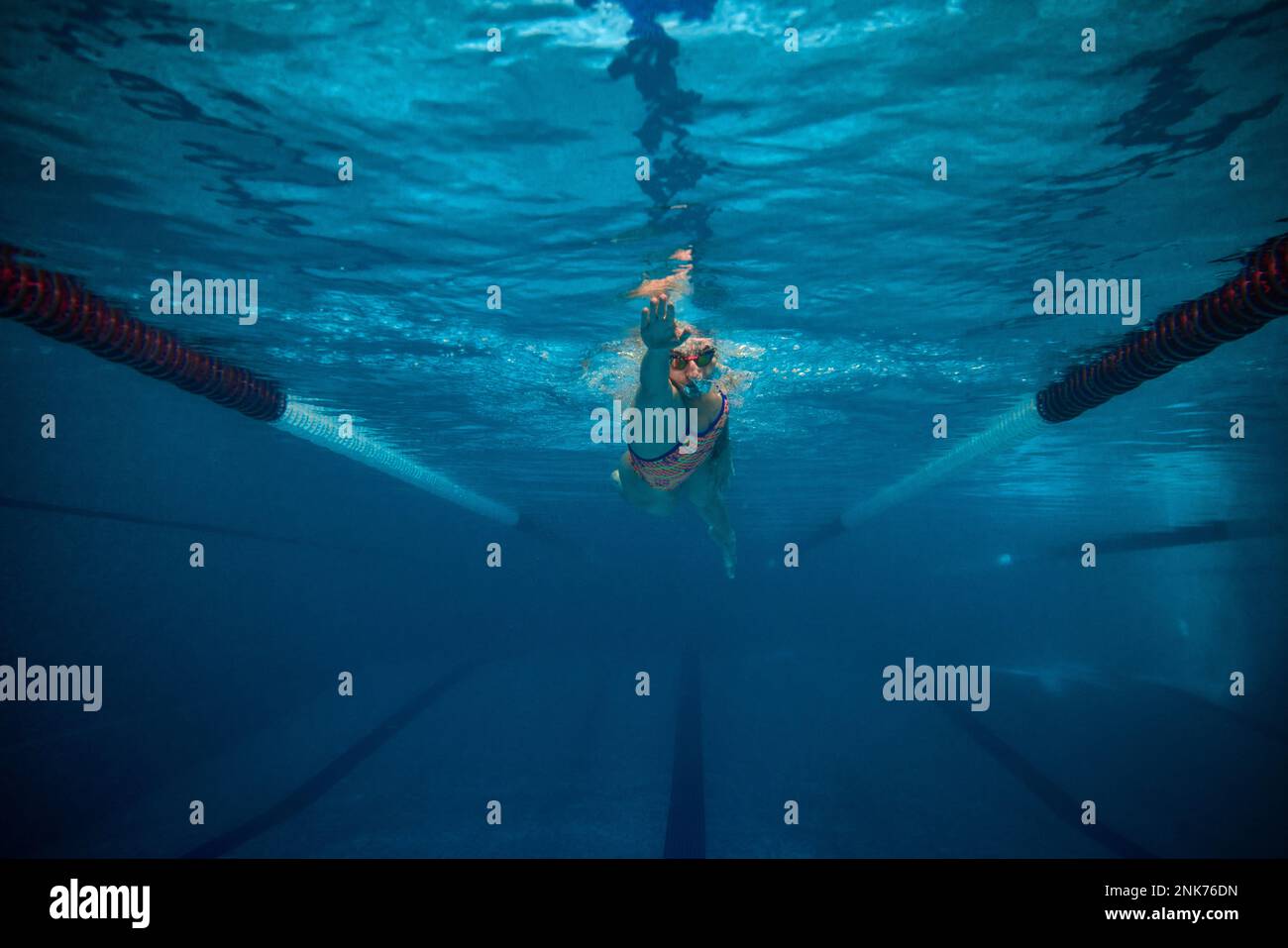 Fast and strong. Professional female swimmer in cap and goggles in ...