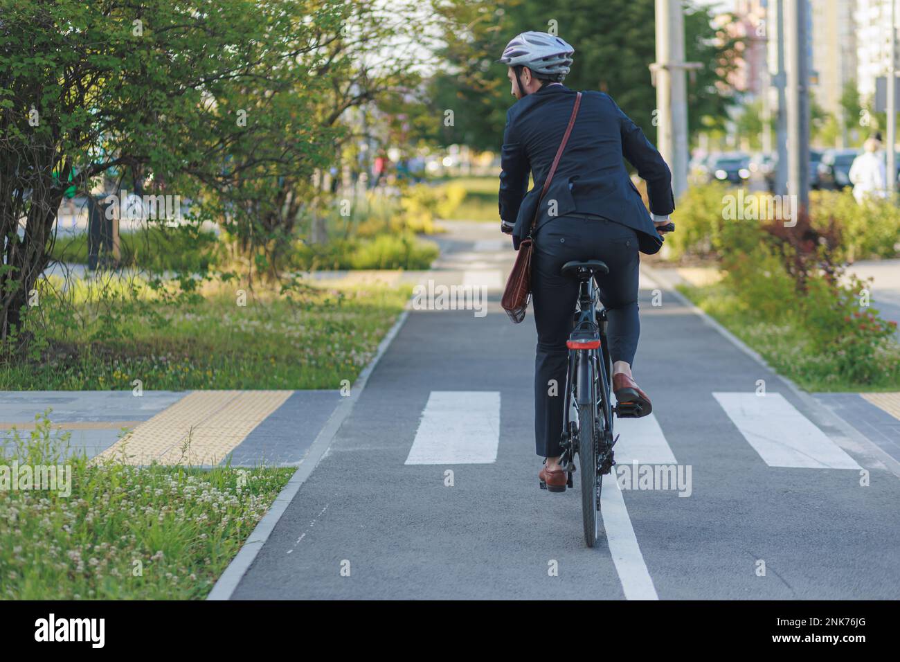 Unrecognizable middle-aged executive in black suit riding on bike lane ...