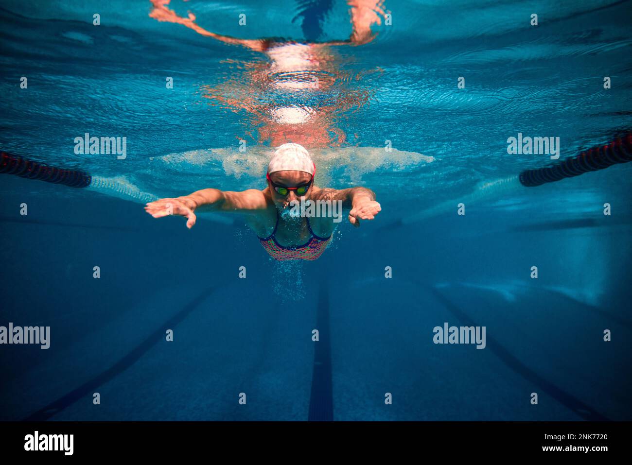 Fast and strong. Professional female swimmer in cap and goggles in ...