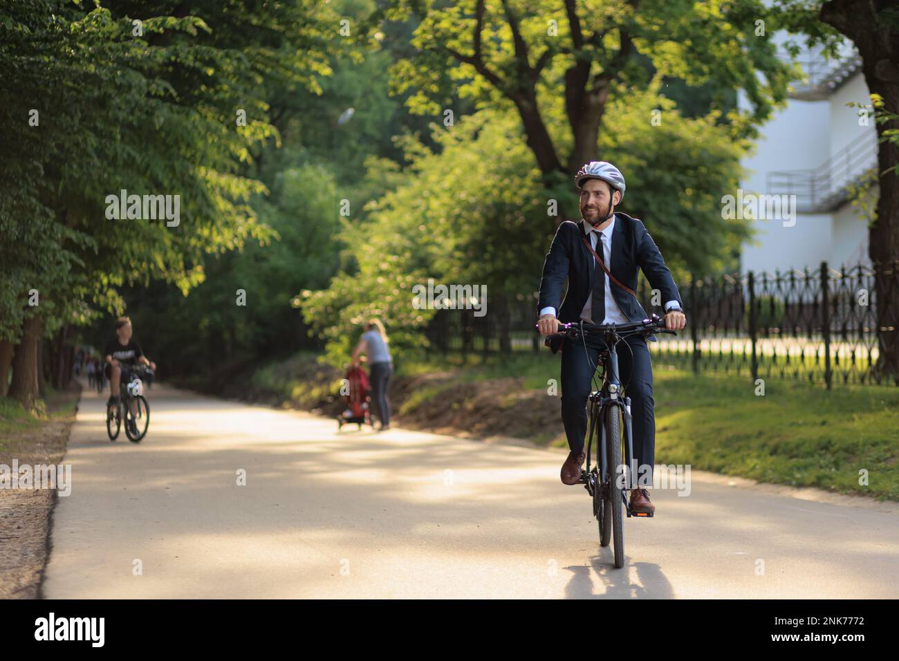 Happy male executive in business outfit returning from job on bicycle ...