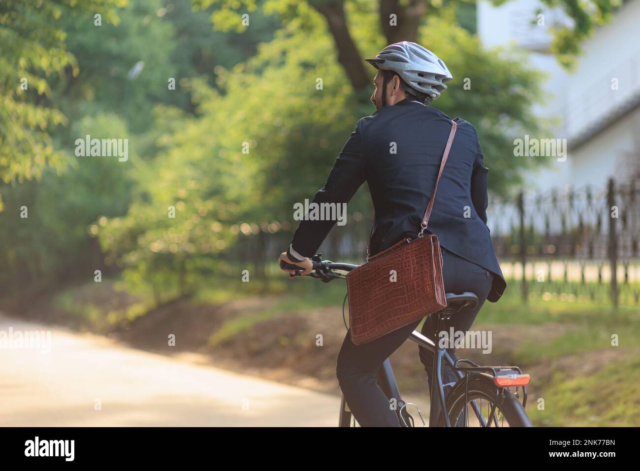 Busy male employee in black suit cycling on bike on paved road to ...