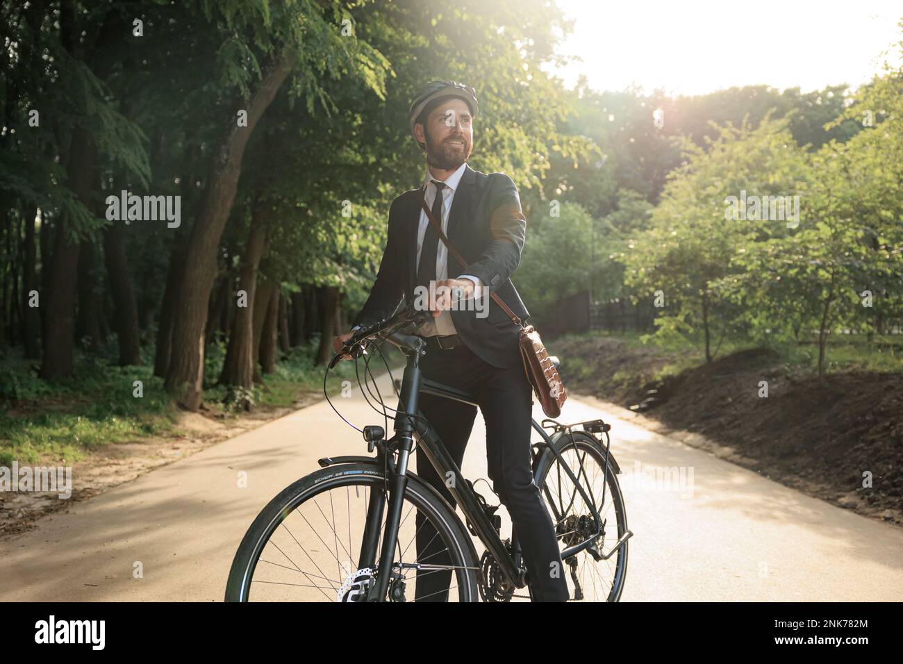 Male manager wearing suit, riding on bike on paved road, while getting ...