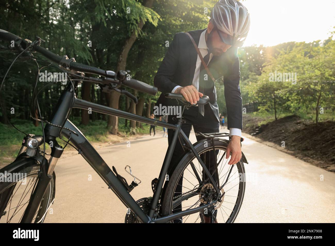 Male caucasian employee in helmet leaning, while checking bike wheel ...