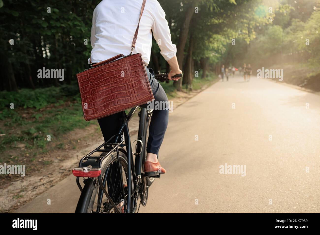 Back view of male employee in stylish clothes cycling on bike to work ...