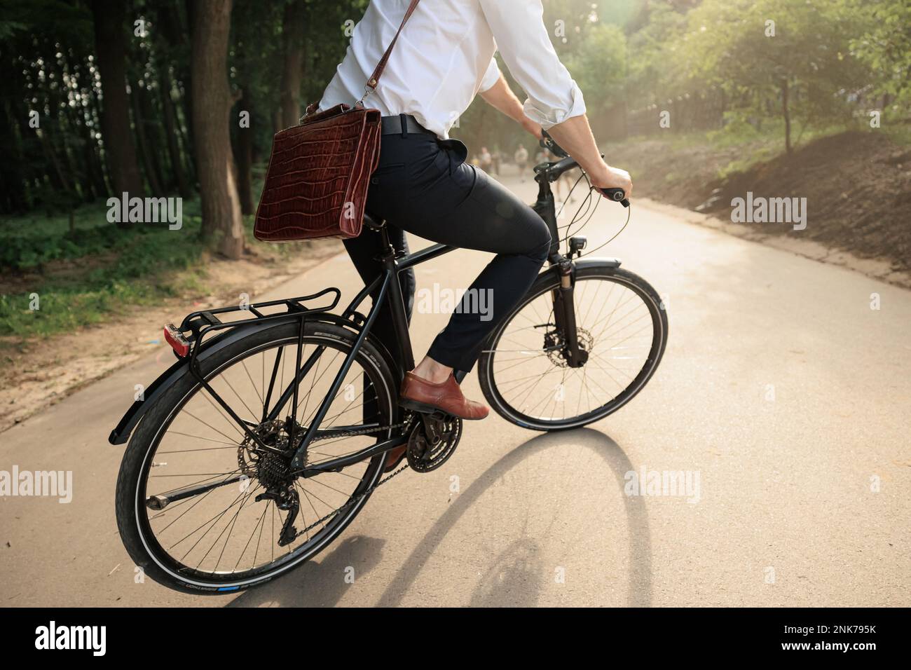 Male worker in smart casual clothes cycling on bike from job along city ...