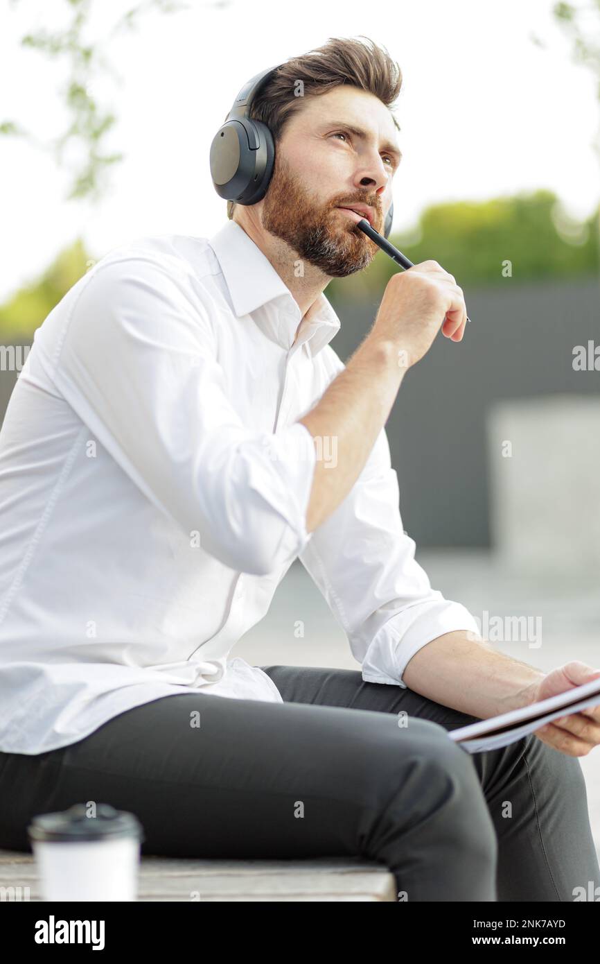 Stylish male manager touching lips with pen in thoughtful gesture and ...