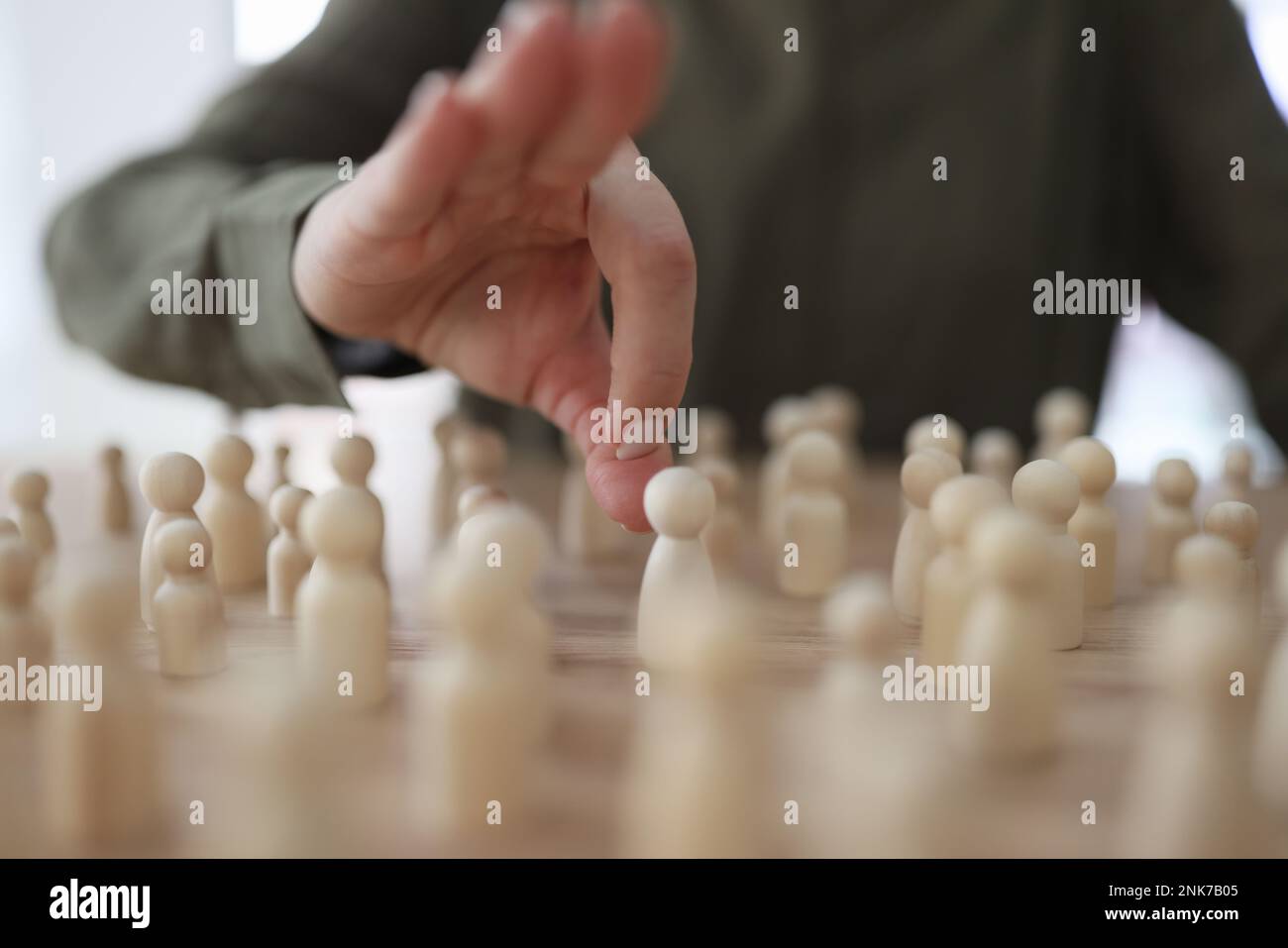 The hand pushes wooden figures of men on the table Stock Photo - Alamy