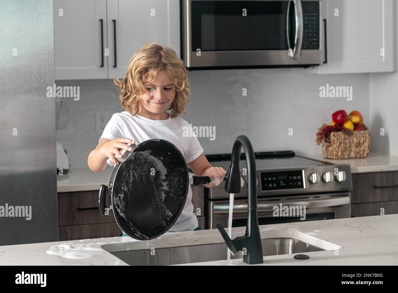 Child helping his parents with housework. Child with sponge with dish ...