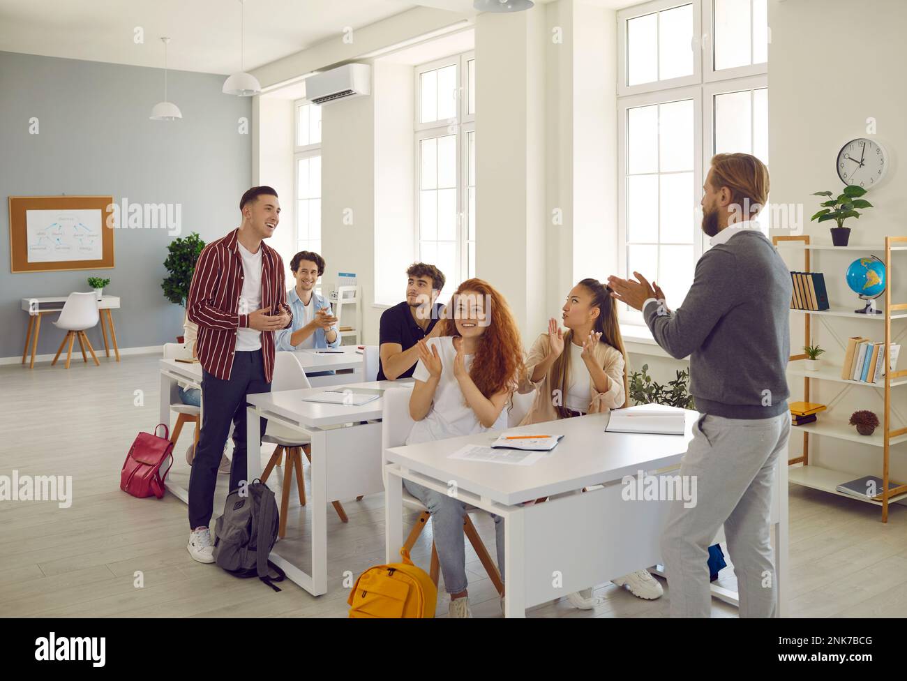 Student answering professor's question standing near his desk in ...