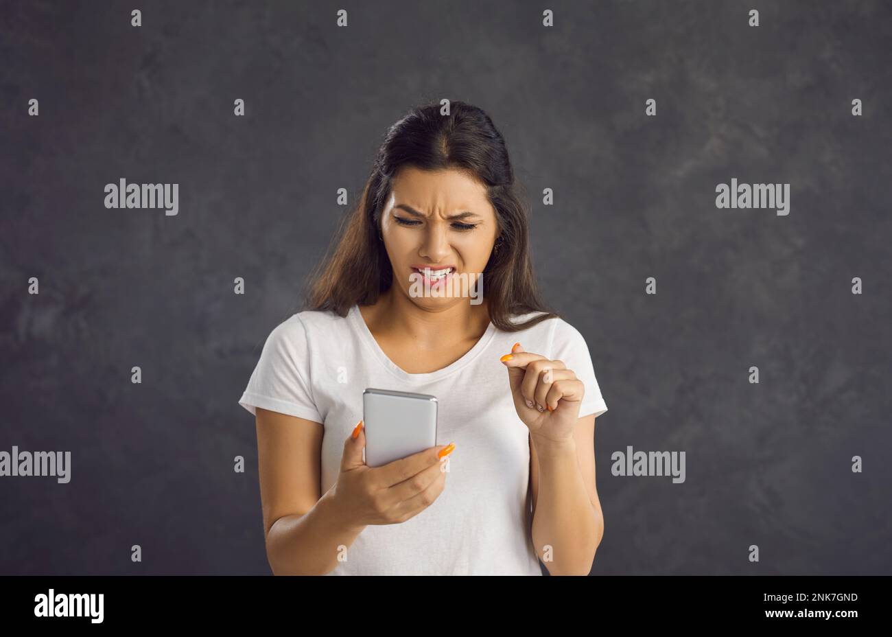 Embarrassed woman looks at screen of her mobile phone with problematic ...