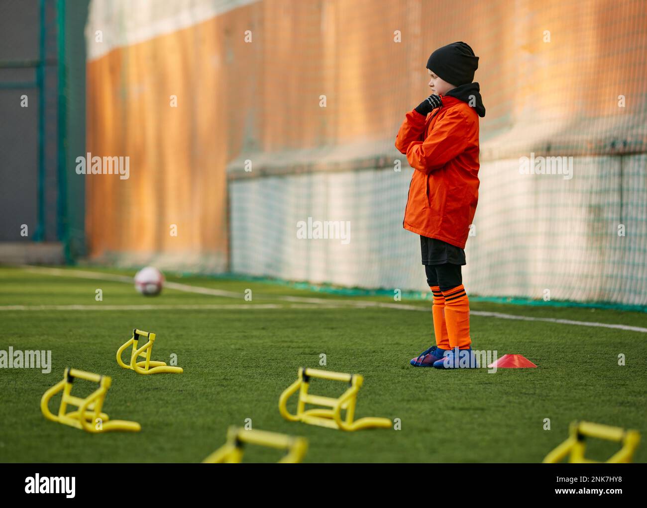 Little boy, child, football player in uniform standing on sports field ...