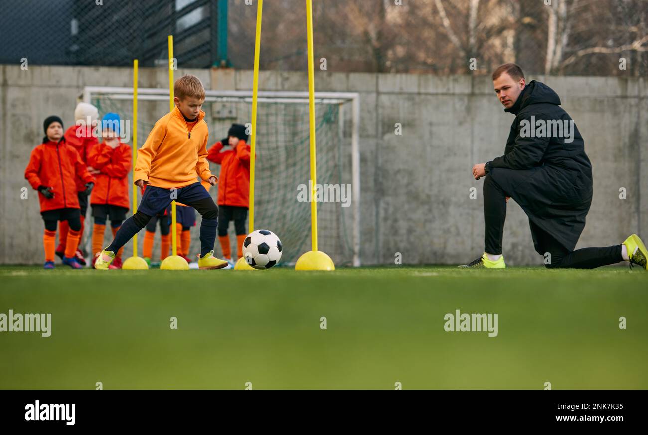 Doing dribbling exercises. Football coach training, teaching kids, boys ...