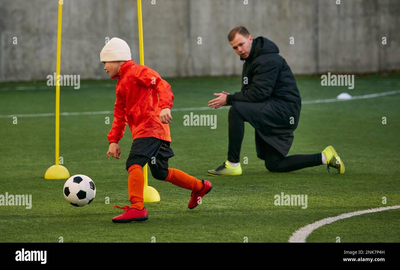 Coach controlling movements. Little boy, child, football player in ...