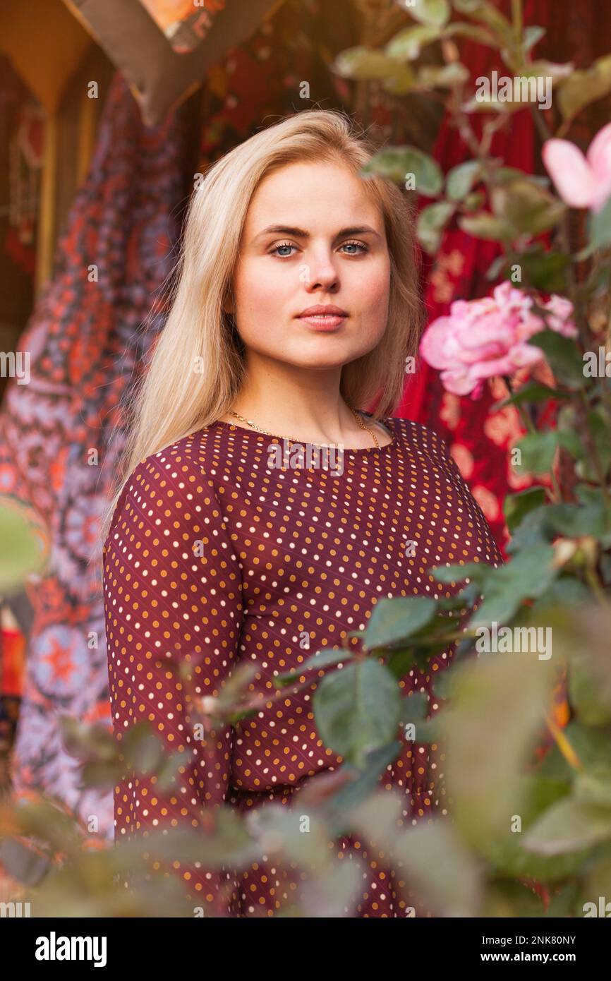 Beautiful blond hair traveler woman wearing red dress stay near rose ...