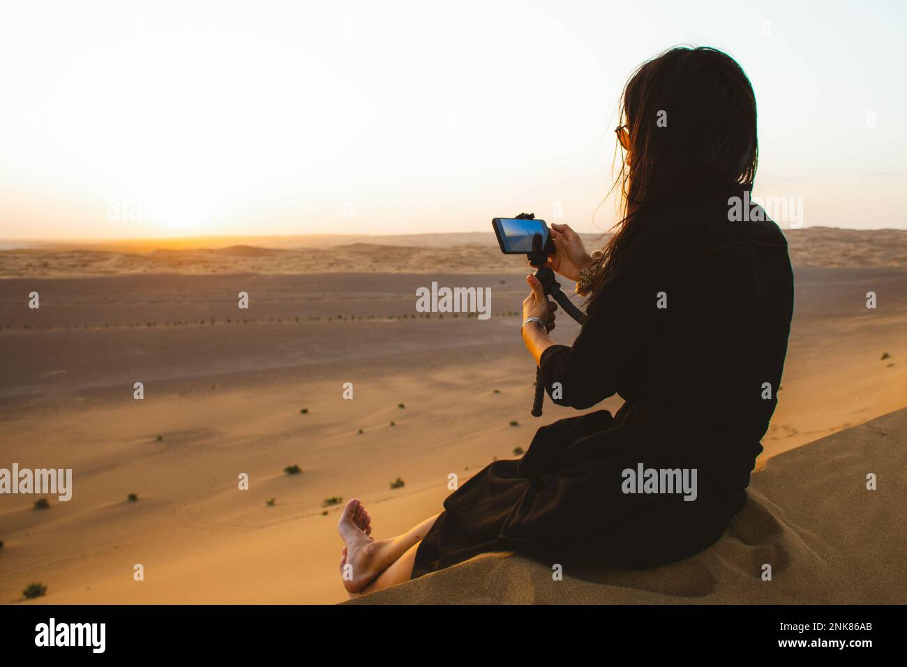Tourist sit enjoy film experience in desert on sand dune at sunset ...