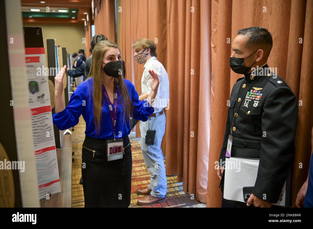 Marine Corps Lt. Col. Scotty Black (right) judges a poster presentation ...