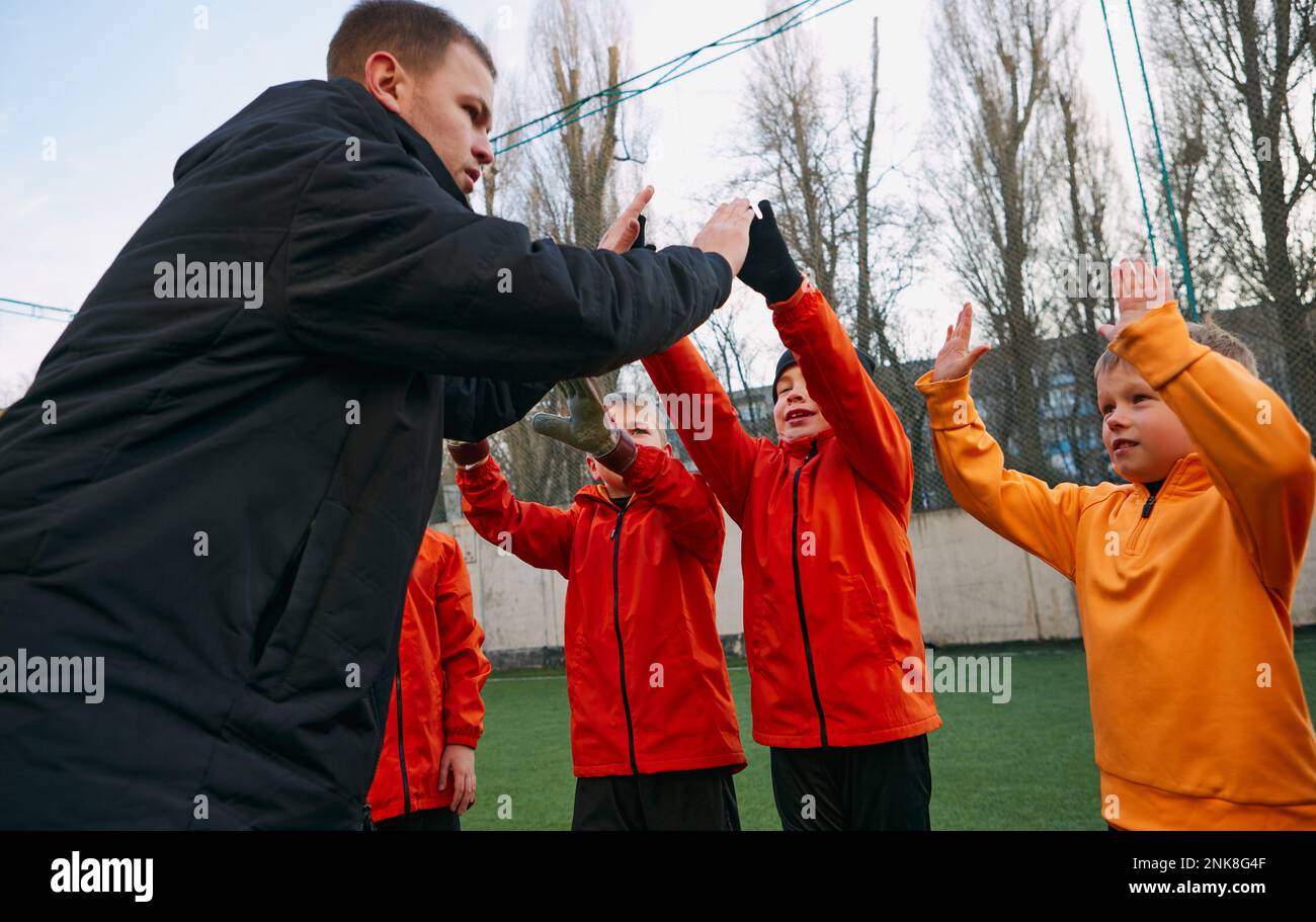 Professional football coach giving high five, cheering kids football ...