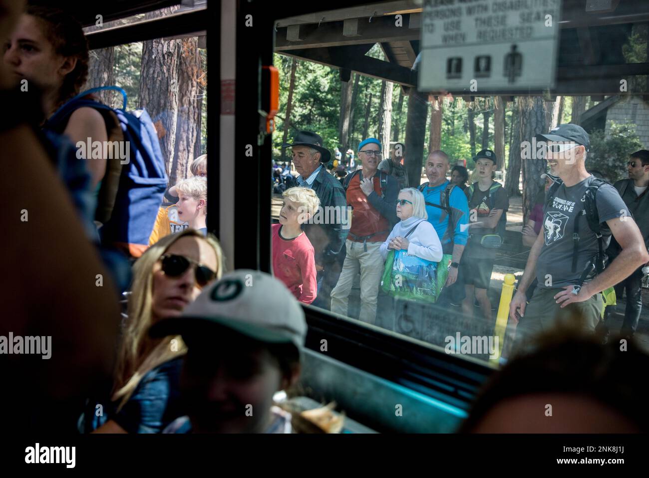 Hikers and tourists line up to board a packed shuttle bus that moves ...