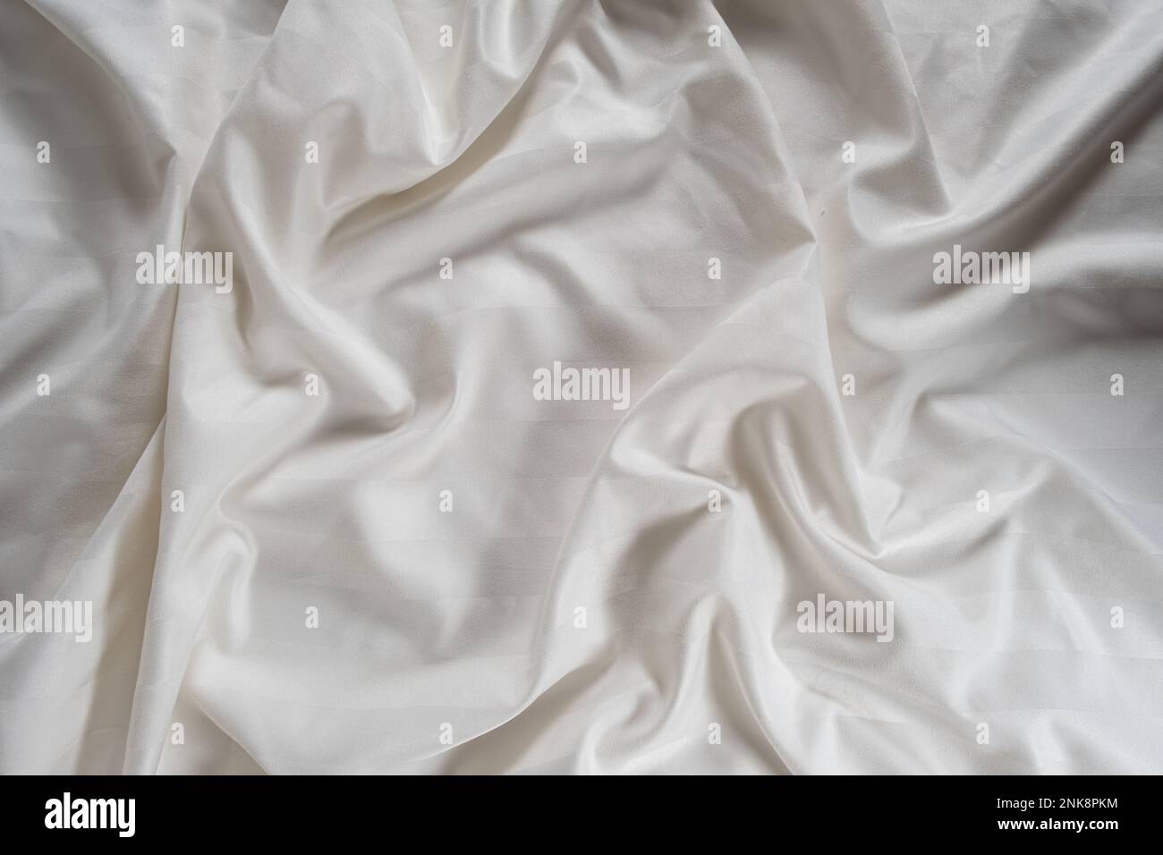 Satin crumpled fabric of light milky color, top view. Natural bed linen ...