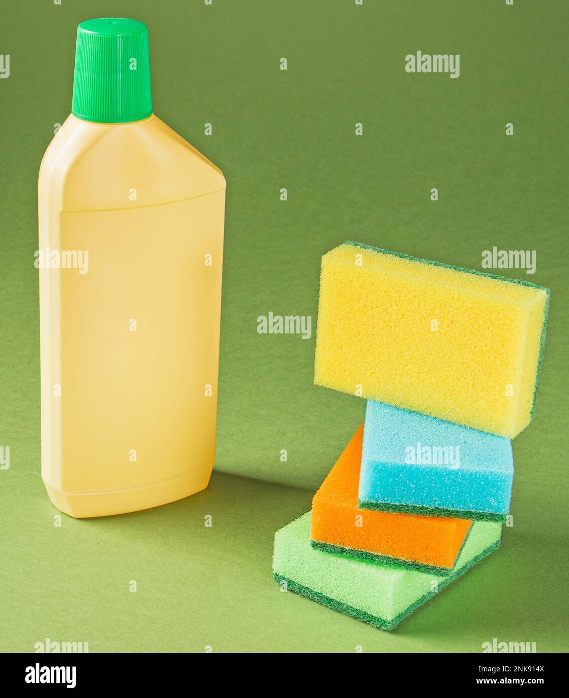 Home cleaning supplies. Bottle with detergent and multi-colored sponges ...