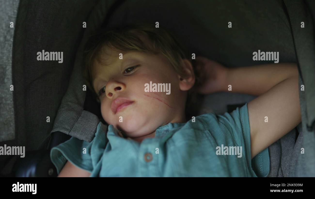 Little boy sitting inside stroller waking up from nap. Child wakes up ...