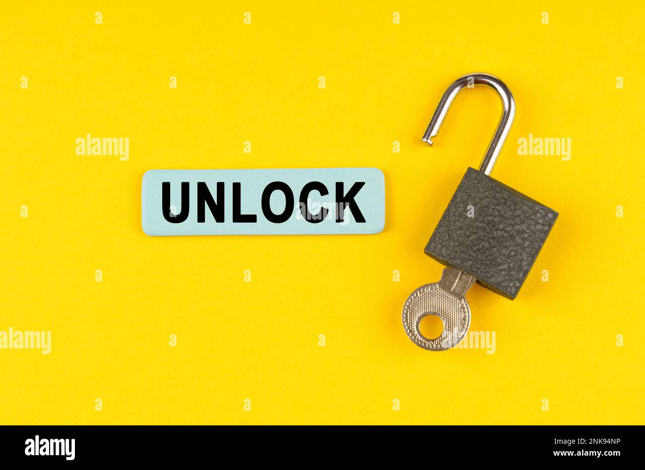 On the yellow surface lies an open lock with a key, next to it is a ...