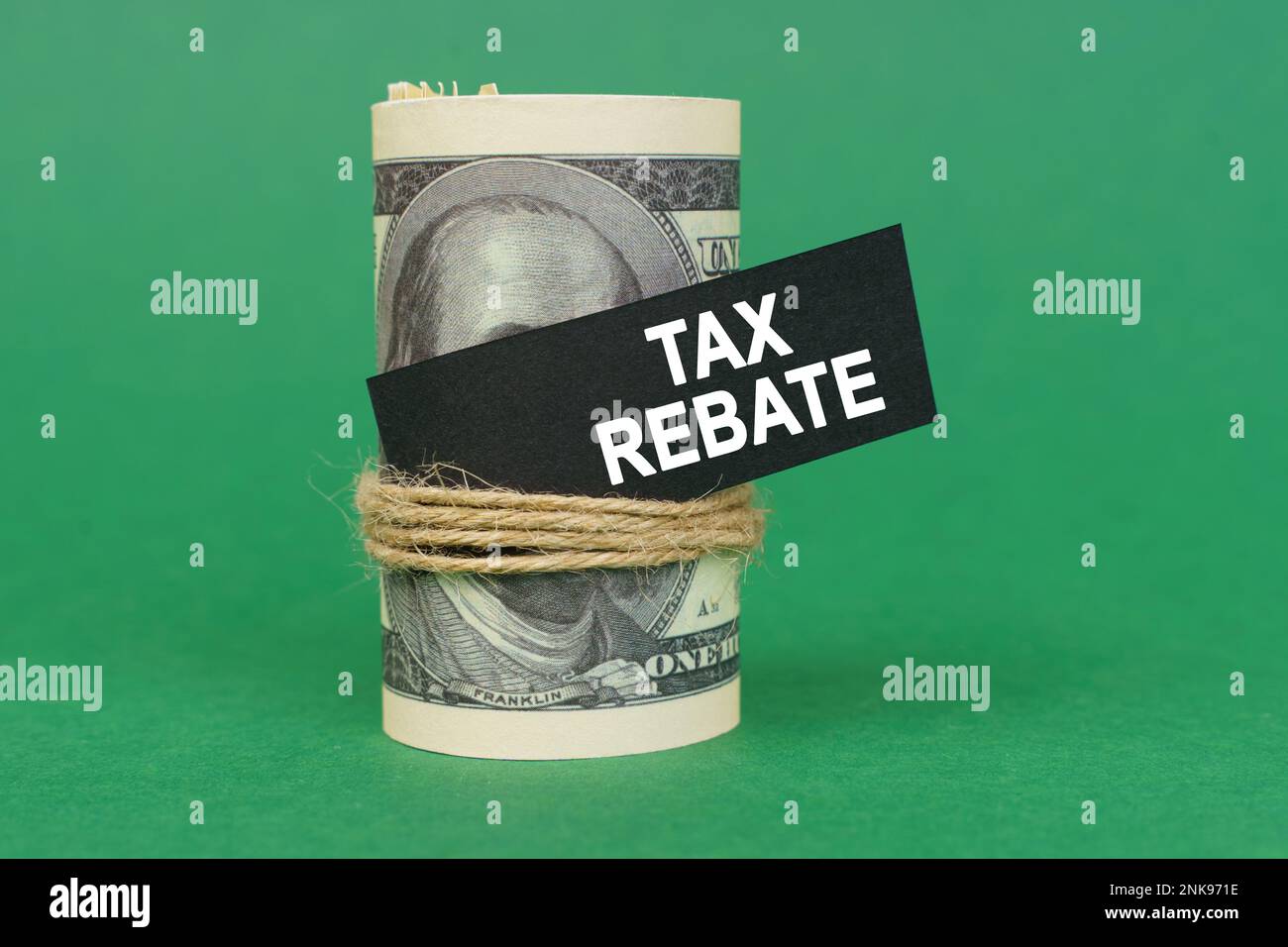 Business concept. On a green surface, rolled dollars with a black sign ...