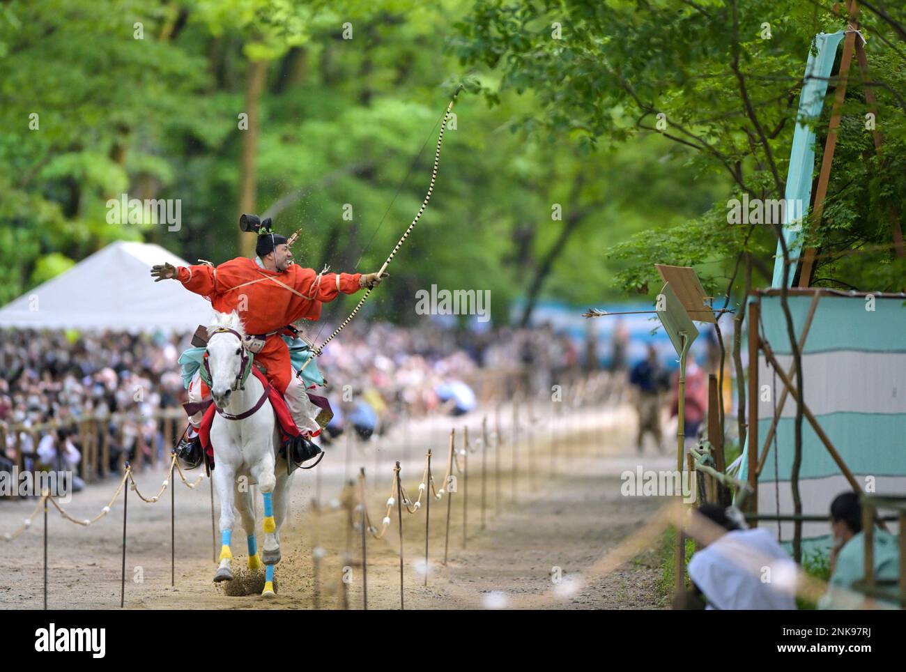 An archer wearing the costumes of court noble on a running horse shoots ...