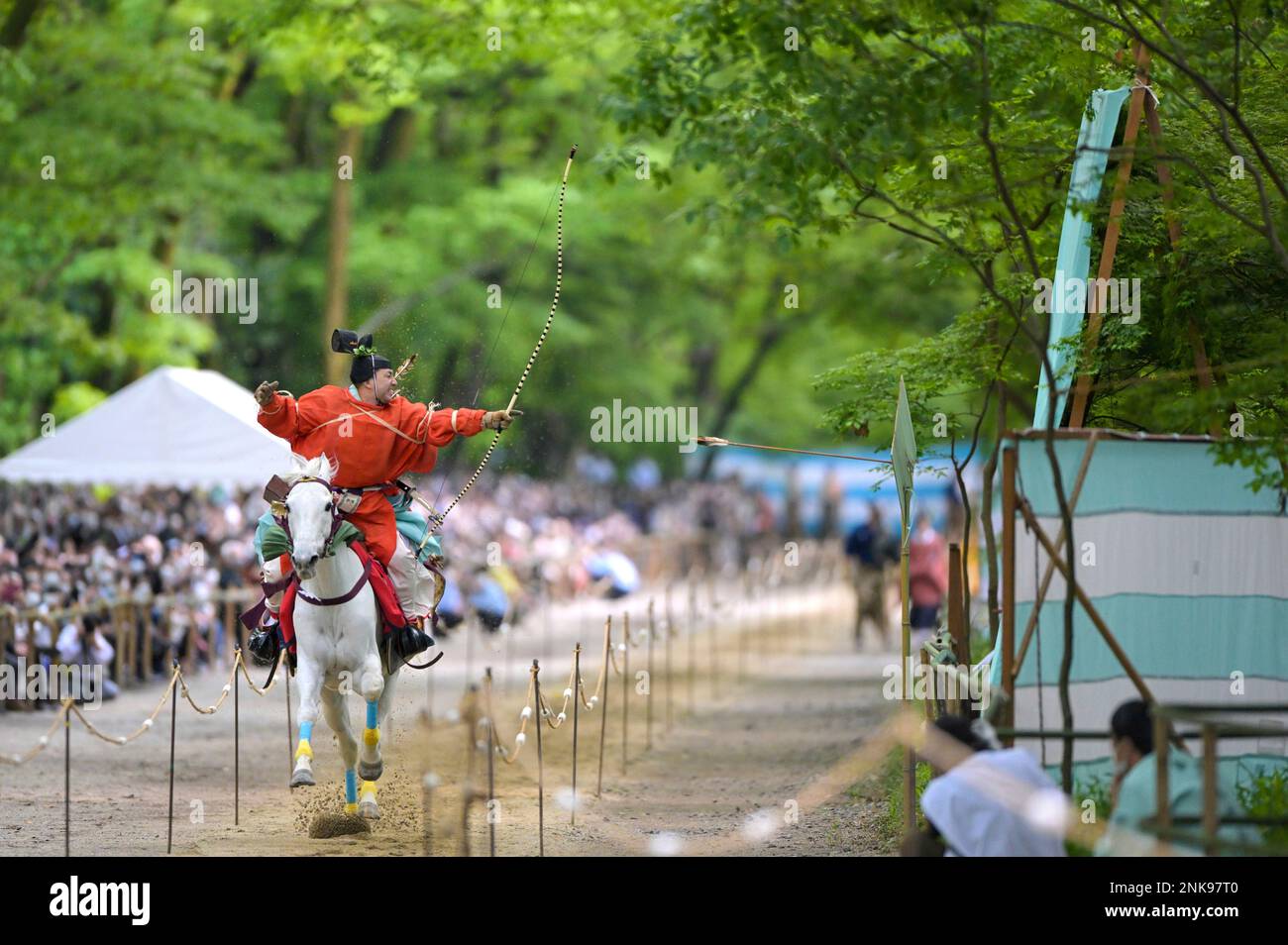 An archer wearing the costumes of court noble on a running horse shoots ...