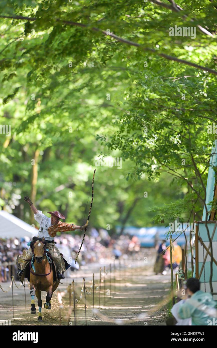 An archer wearing the costumes of court noble on a running horse shoots ...