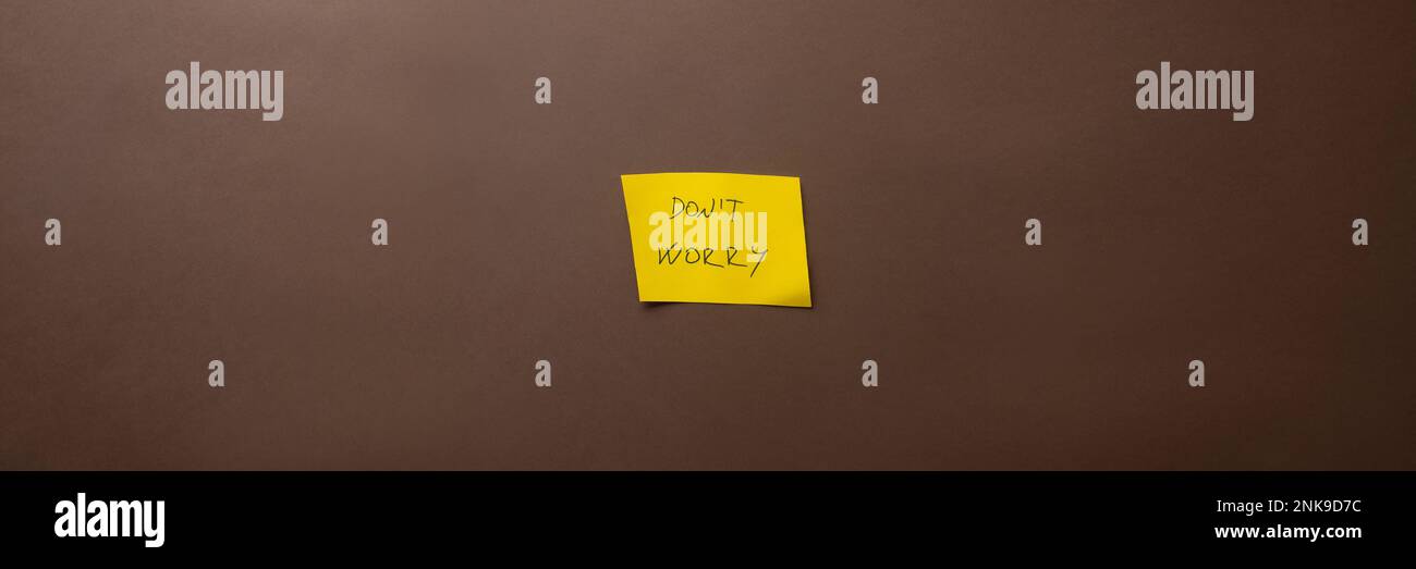 Yellow post it paper with a Dont worry sign on it placed over a brown ...