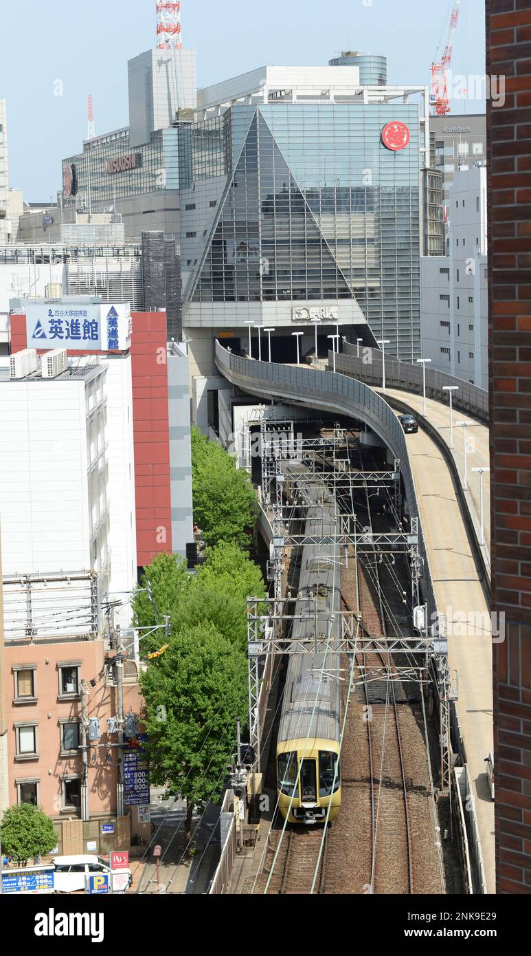 A train of Nishi-Nippon Railroad Co., Ltd. runs between buildings ...